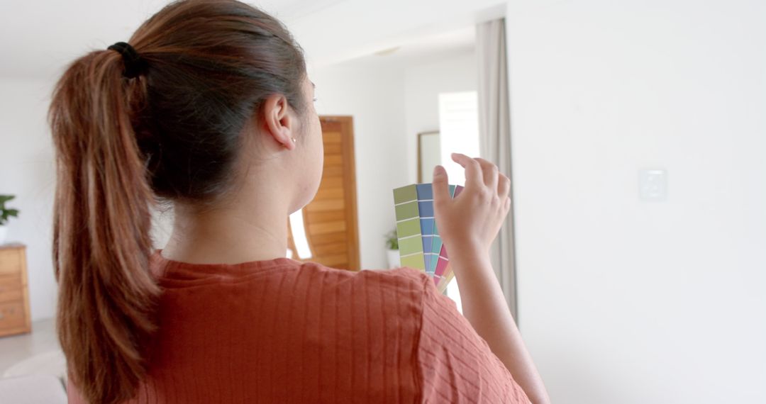 Woman choosing paint colors in sunlit living room for home renovation ...