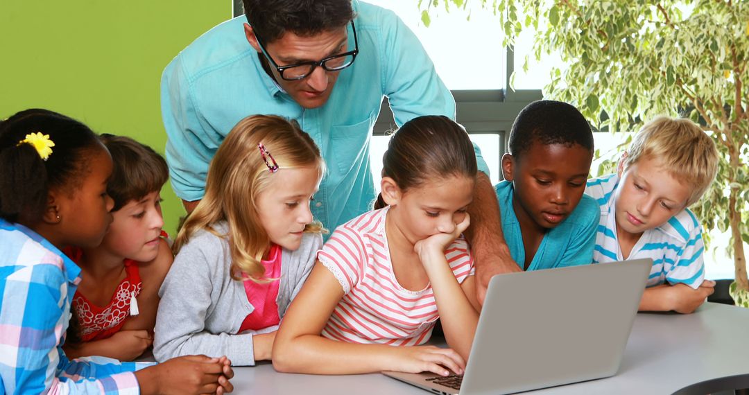 Teacher Guiding Diverse Students Using Laptop in Classroom from Pikwizard