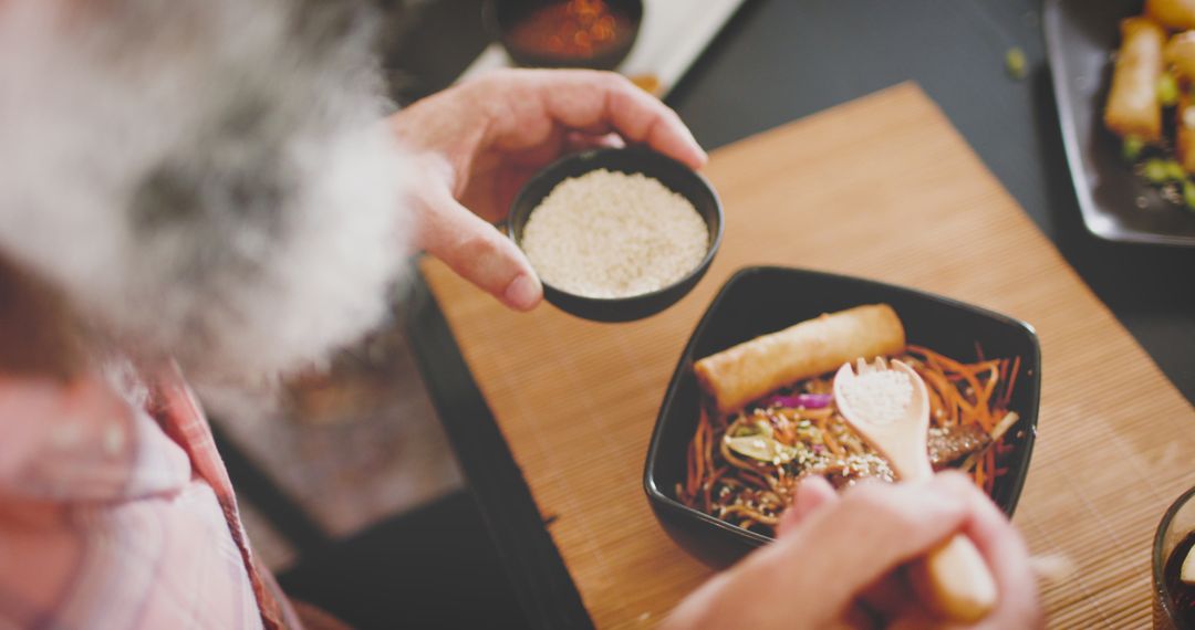 Man Sprinkling Sesame Seeds on Asian-Inspired Meal Preparation