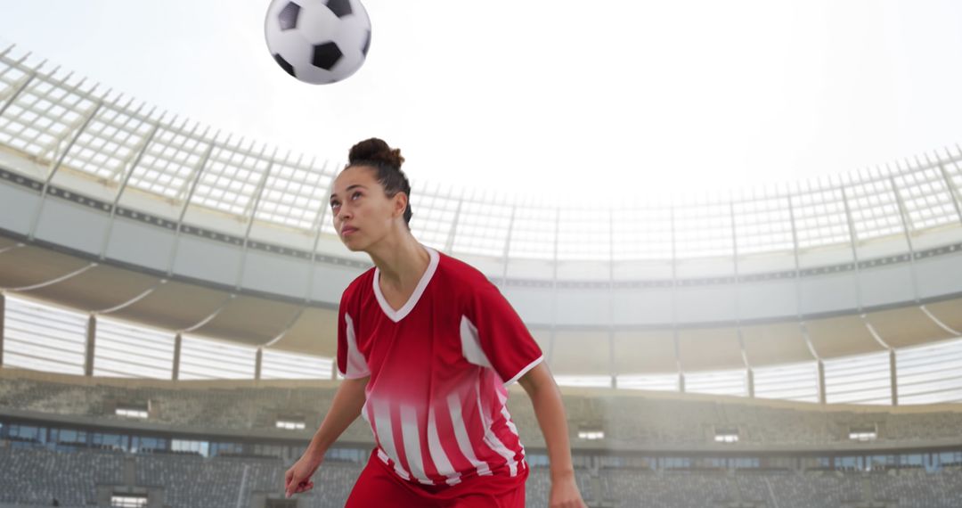 Female Soccer Player Heading Ball in Stadium