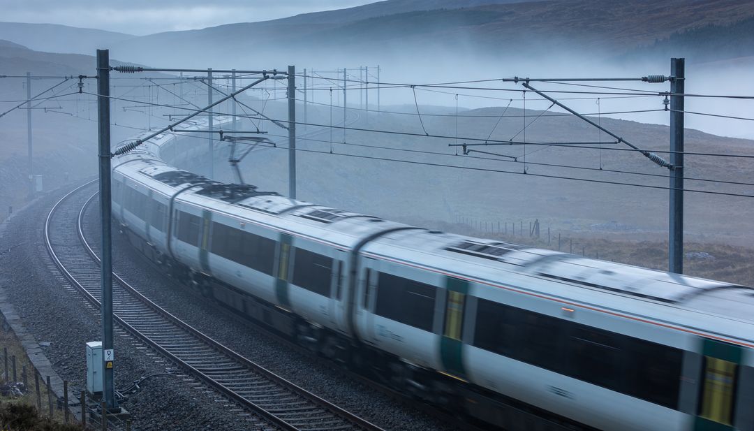 Electric Commuter Train Rounding Foggy Moorland Curve with Overhead ...