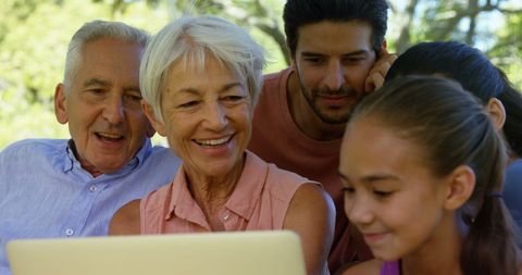 A multigenerational group joyfully shares a tech experience outdoors ...