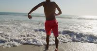 Man Running into Ocean Waves at Sunny Beach from Pikwizard