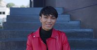 Smiling Transgender Man in Bold Red Jacket Relaxing on City Steps ...