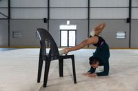 Female Gymnast Practicing Handstand with Chair in Gym from Pikwizard