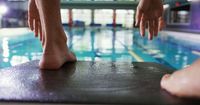 Swimmer Preparing for Dive at Indoor Pool with Focused Feet on Starting ...